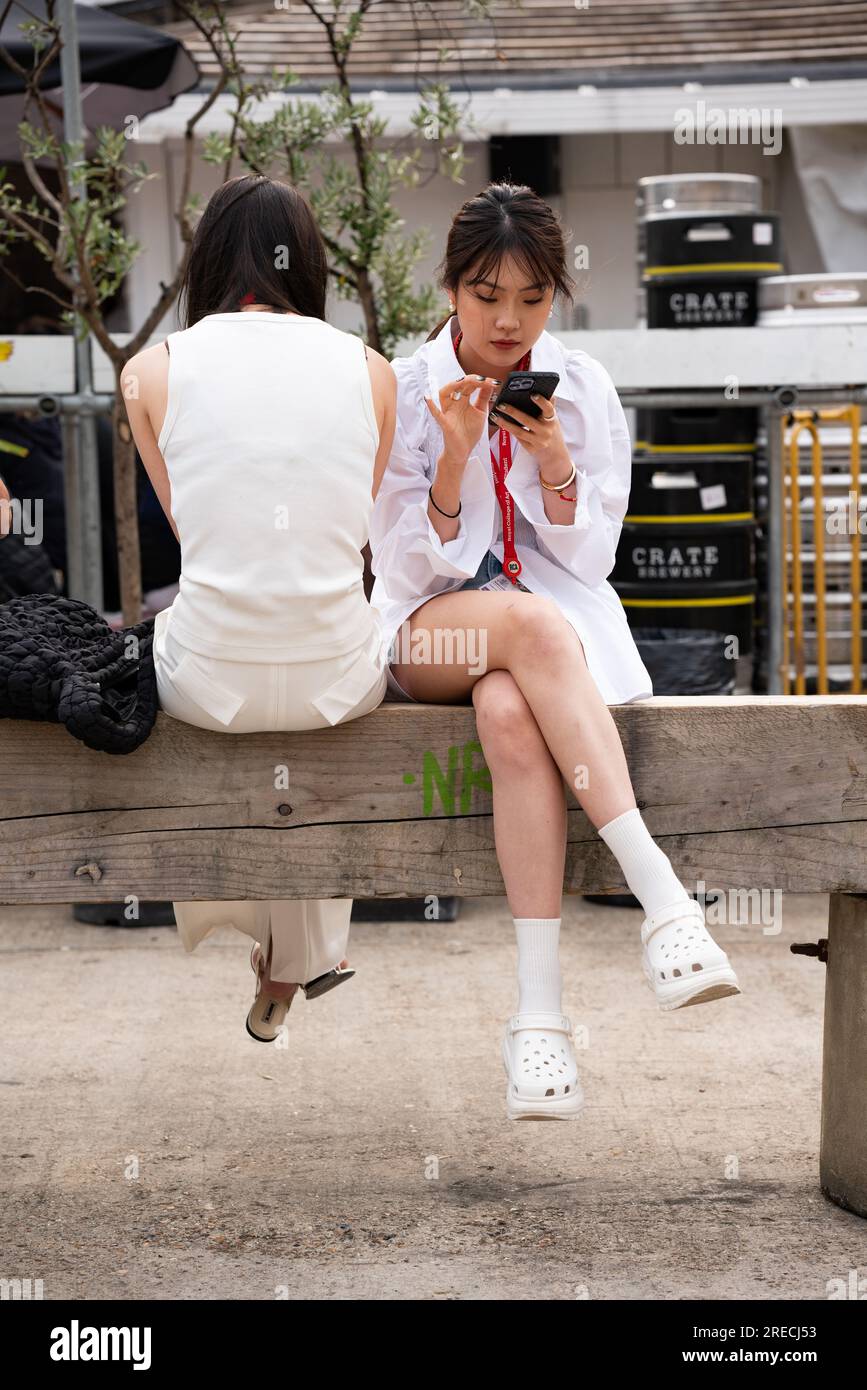 Two asian female students sitting texting on iphones at Royal College ...