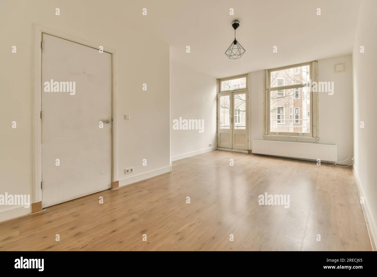an empty room with wooden floors and white walls, there is a door ...