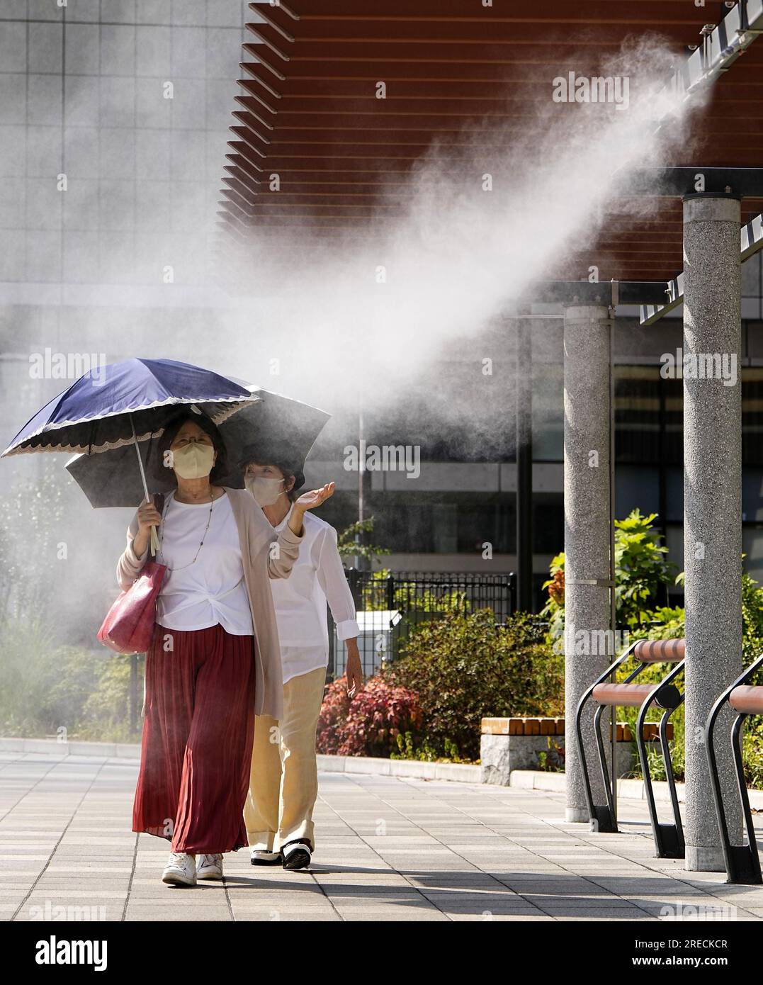 People walk under mist showers on a sweltering hot day in Tokyo's Ginza ...