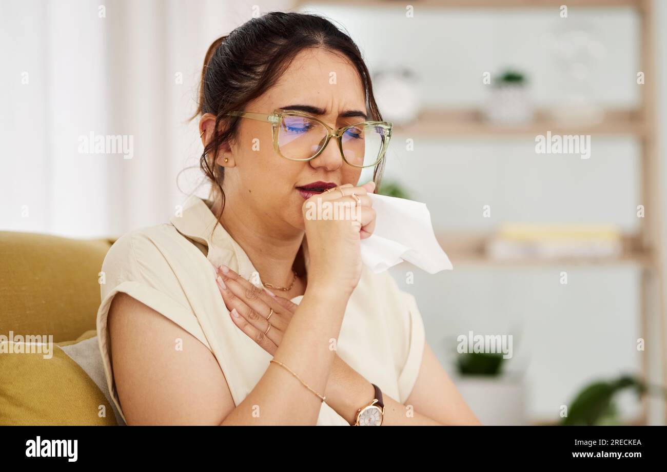 Coughing, tissue and sick woman on a sofa with cold, flu or sore throat in her home. Allergies ...