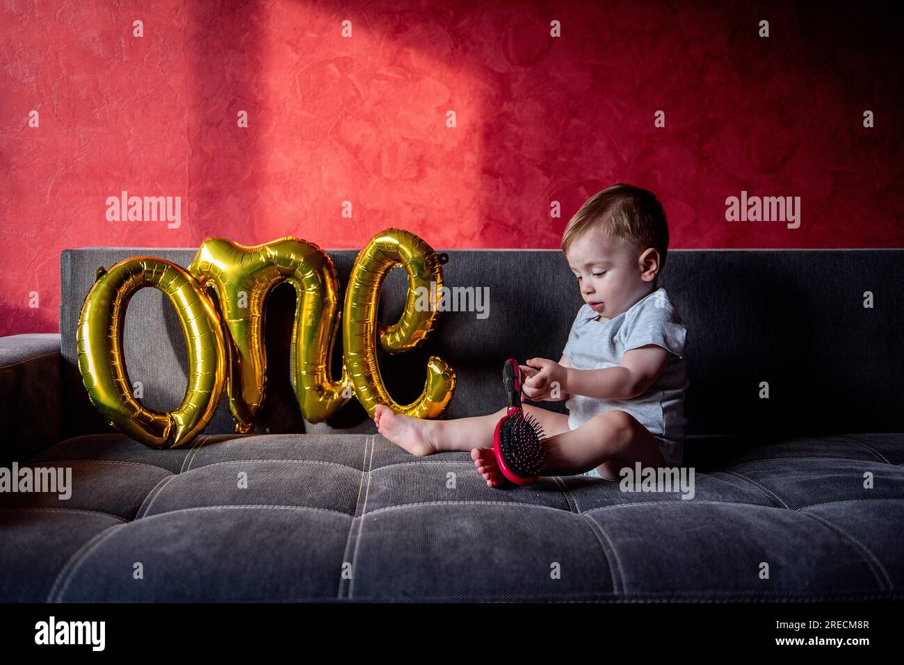 First birthday party, baby plays with gold colored foil balloons ONE ...