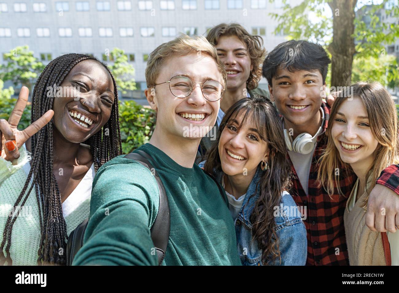 A group of multicultural teenagers with backpacks take a selfie in ...