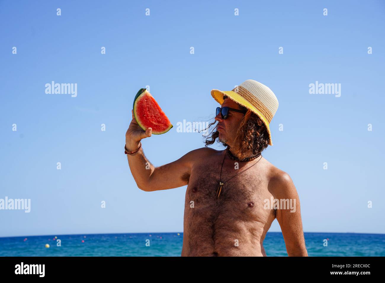 Portrait of a mature guy with a watermelon on the beach. Safety, toxic ...