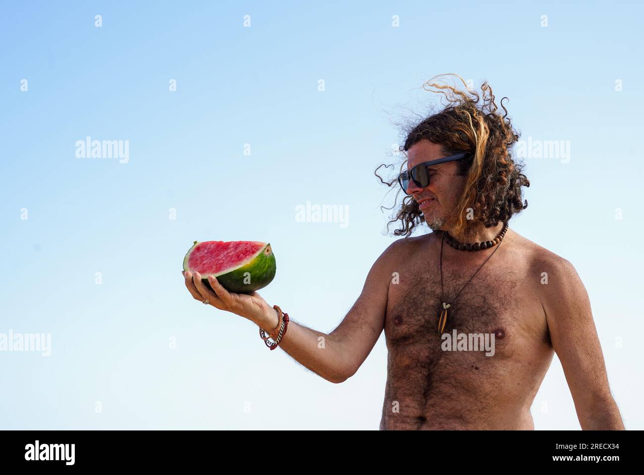 Portrait of a funny mature man with a watermelon on the beach. Safety ...