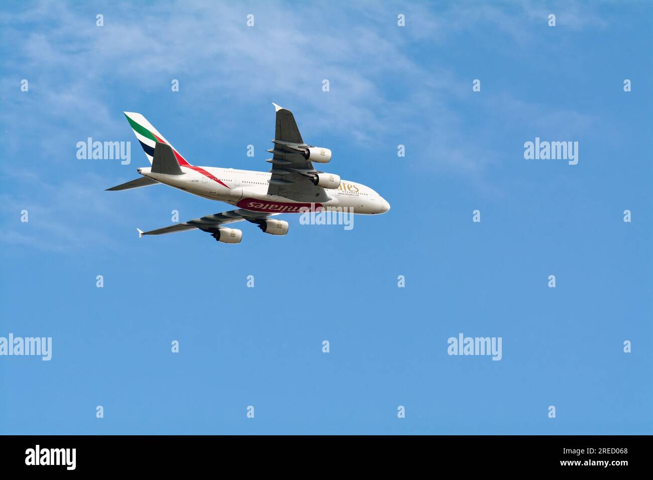A low flying Emirates Airbus 380-861 passenger aircraft against a blue ...