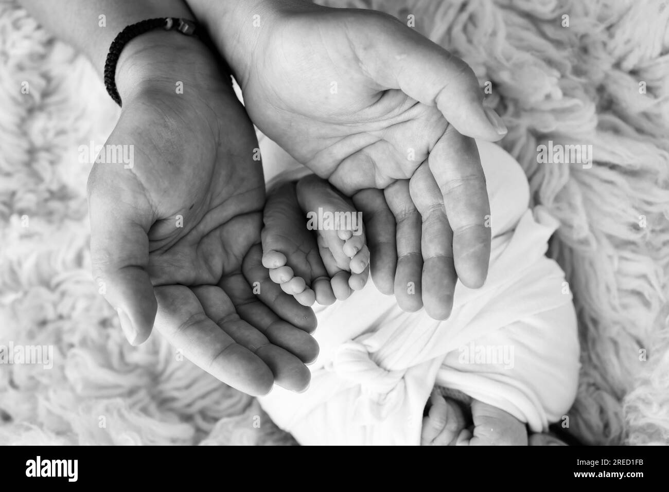 The palms of the father and mother are holding the foot of the newborn ...