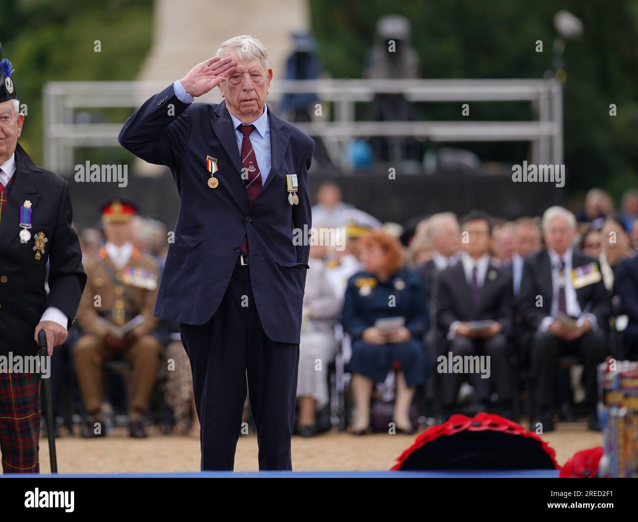 A veteran salutes after laying a poppy sprig to fallen comrades during ...