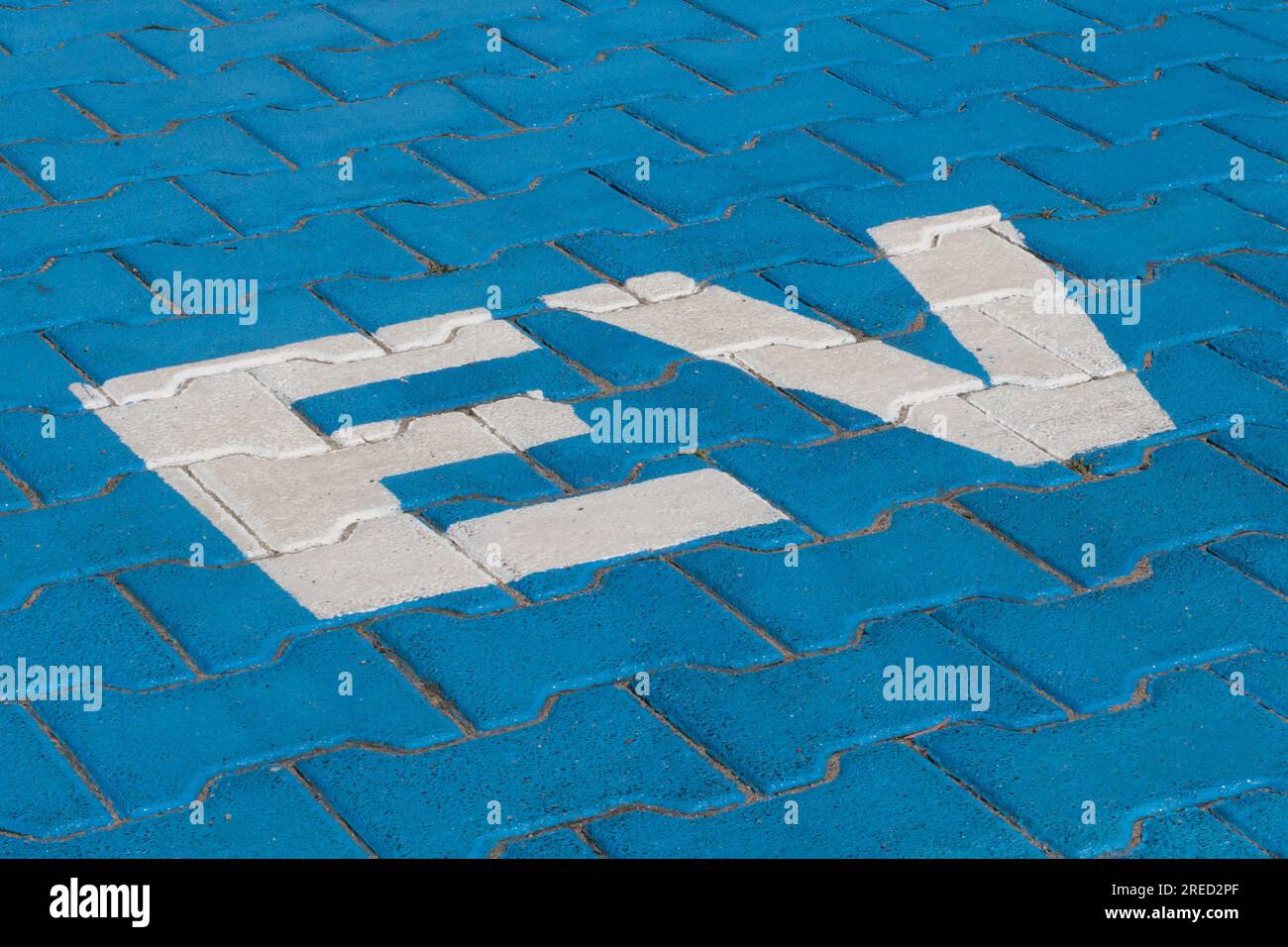 A designated parking space in a lot, marked with the 'EV' symbol on the ...