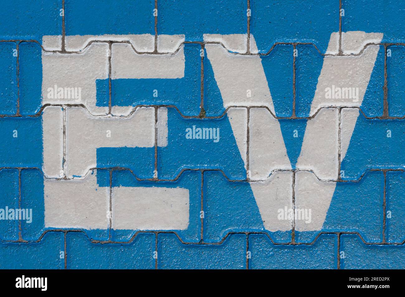 A parking spot in a lot, marked with the 'EV' symbol on the blue ...