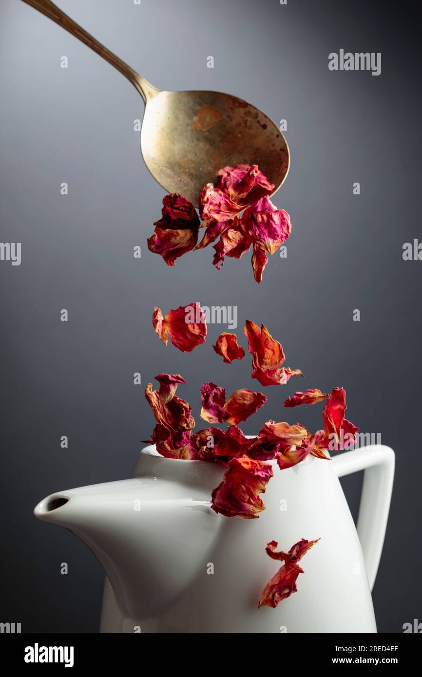 Dried rose petals are poured into a white teapot Stock Photo - Alamy