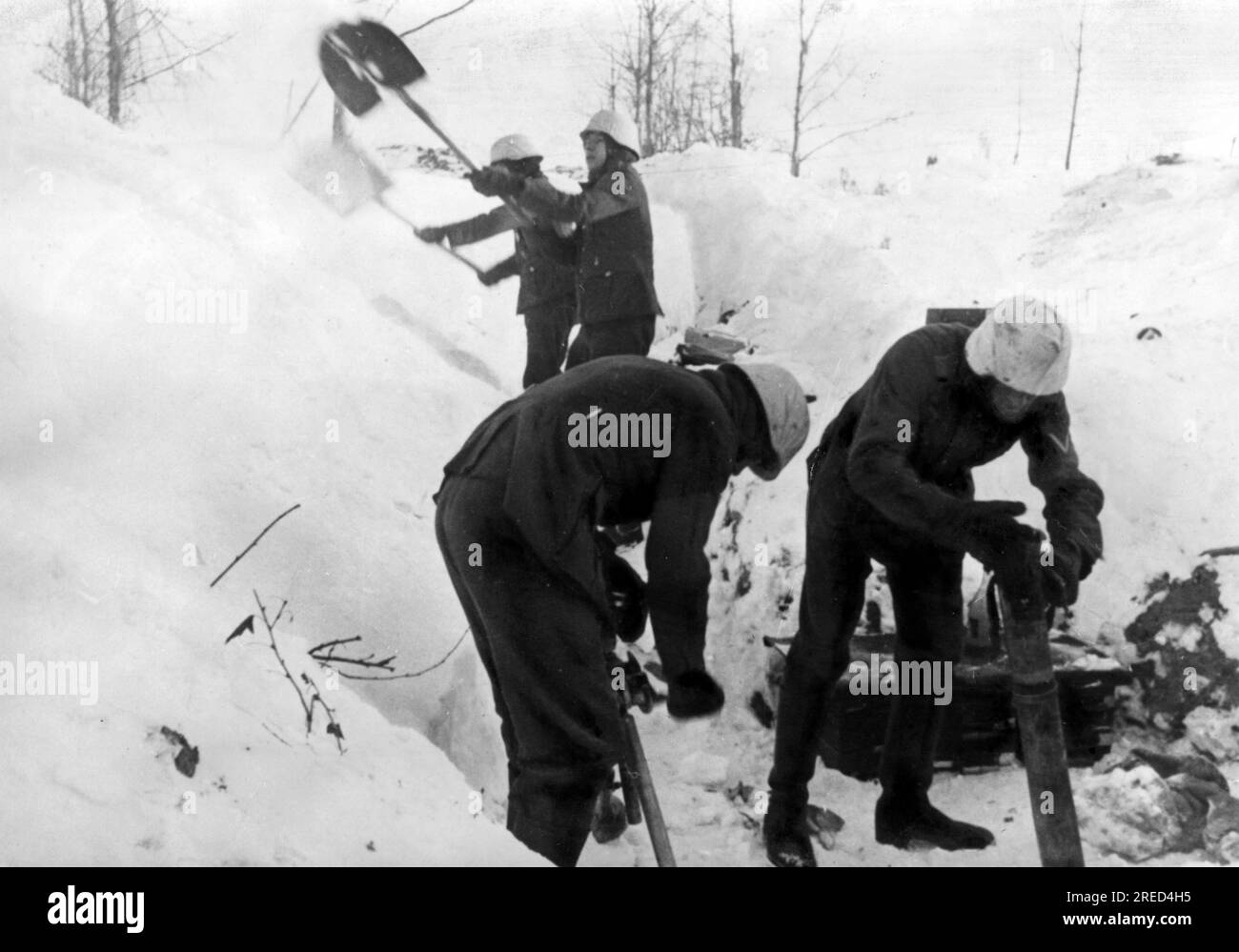 German soldiers shovel snow from the trench while a grenade launcher is ...