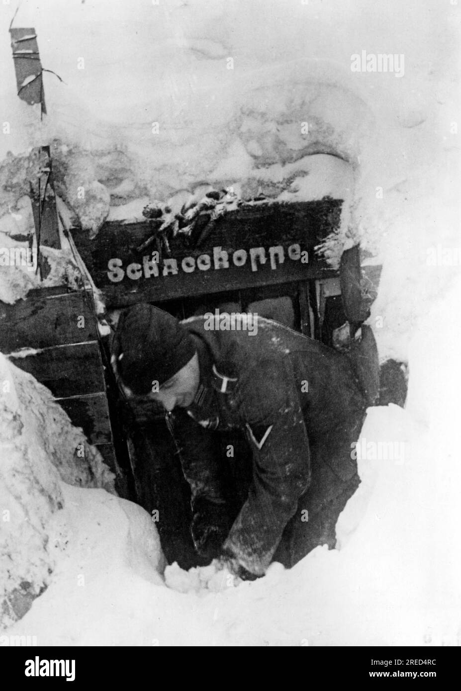 A German soldier shovels snow from the entrance area of his shelter ...