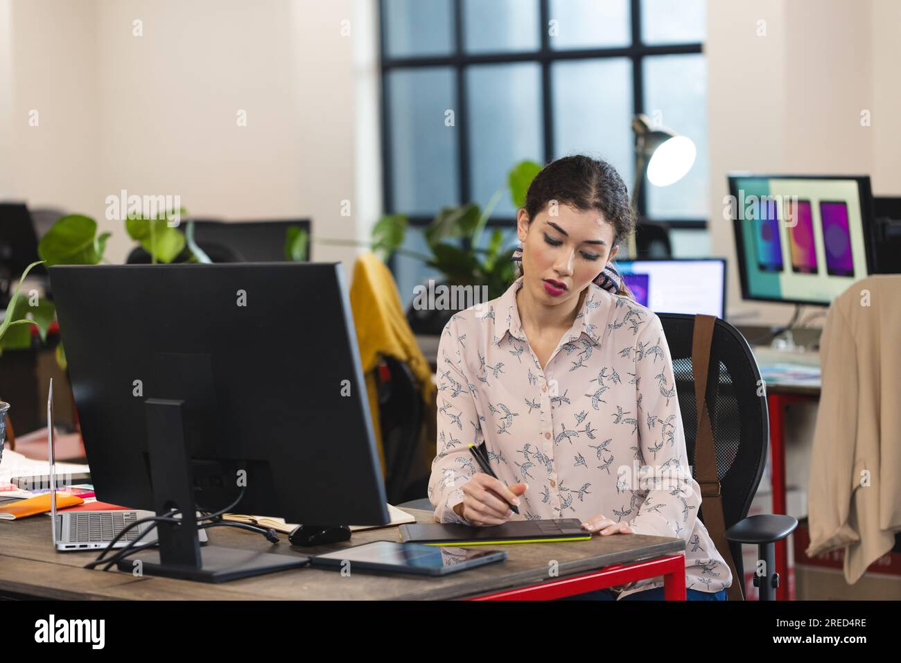 Biracial woman using graphic tablet sitting on her desk at office Stock ...