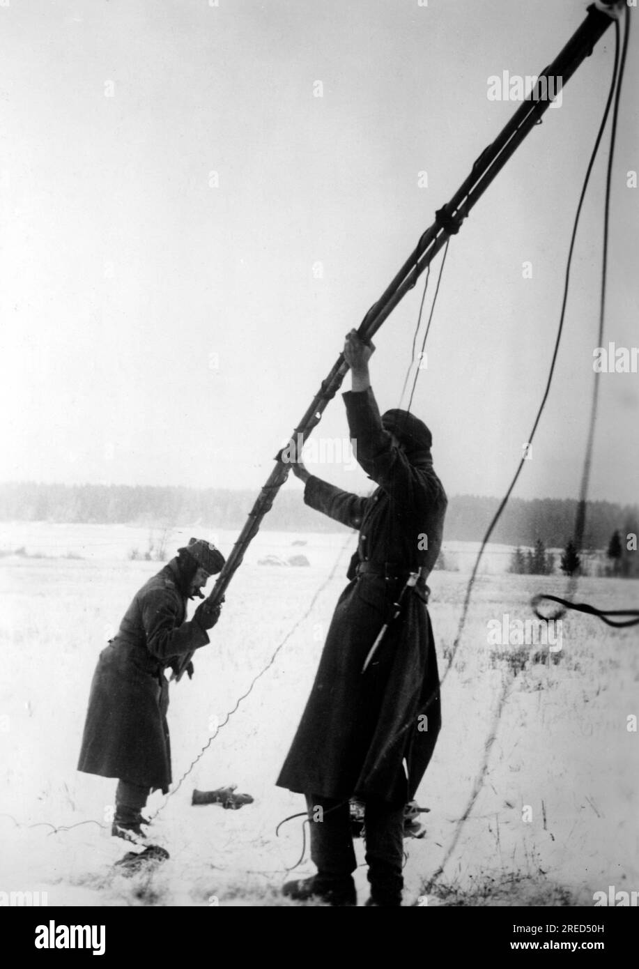 German soldiers lay telephone cable across a road during fighting in ...