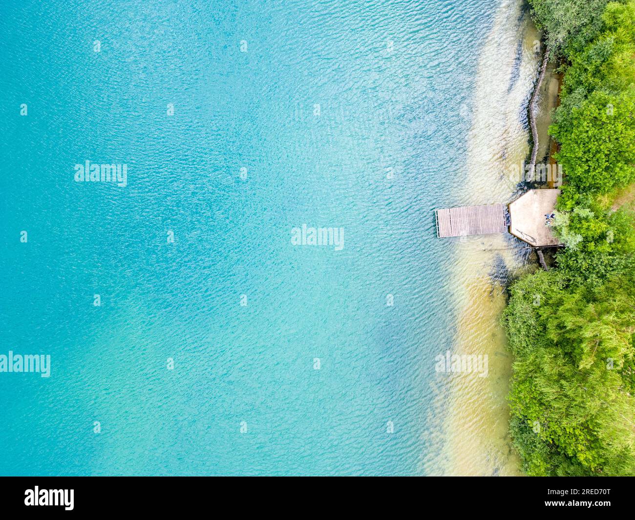 Aerial view of wooden pier leading to the sand lake with clear water ...