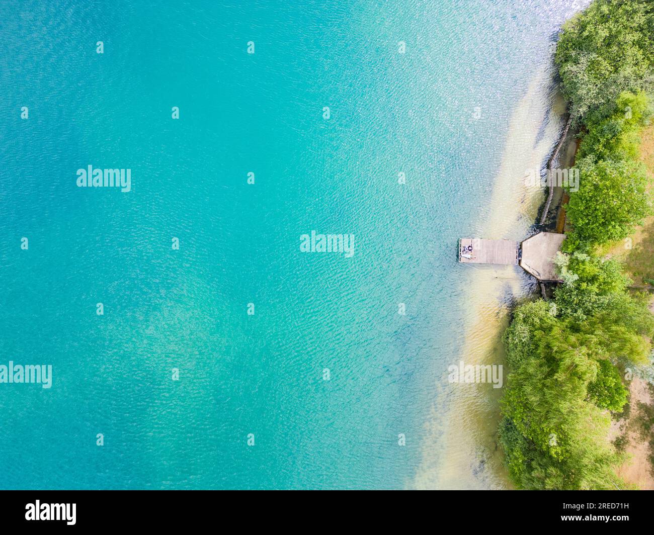 Aerial view of wooden pier leading to the sand lake with clear water ...