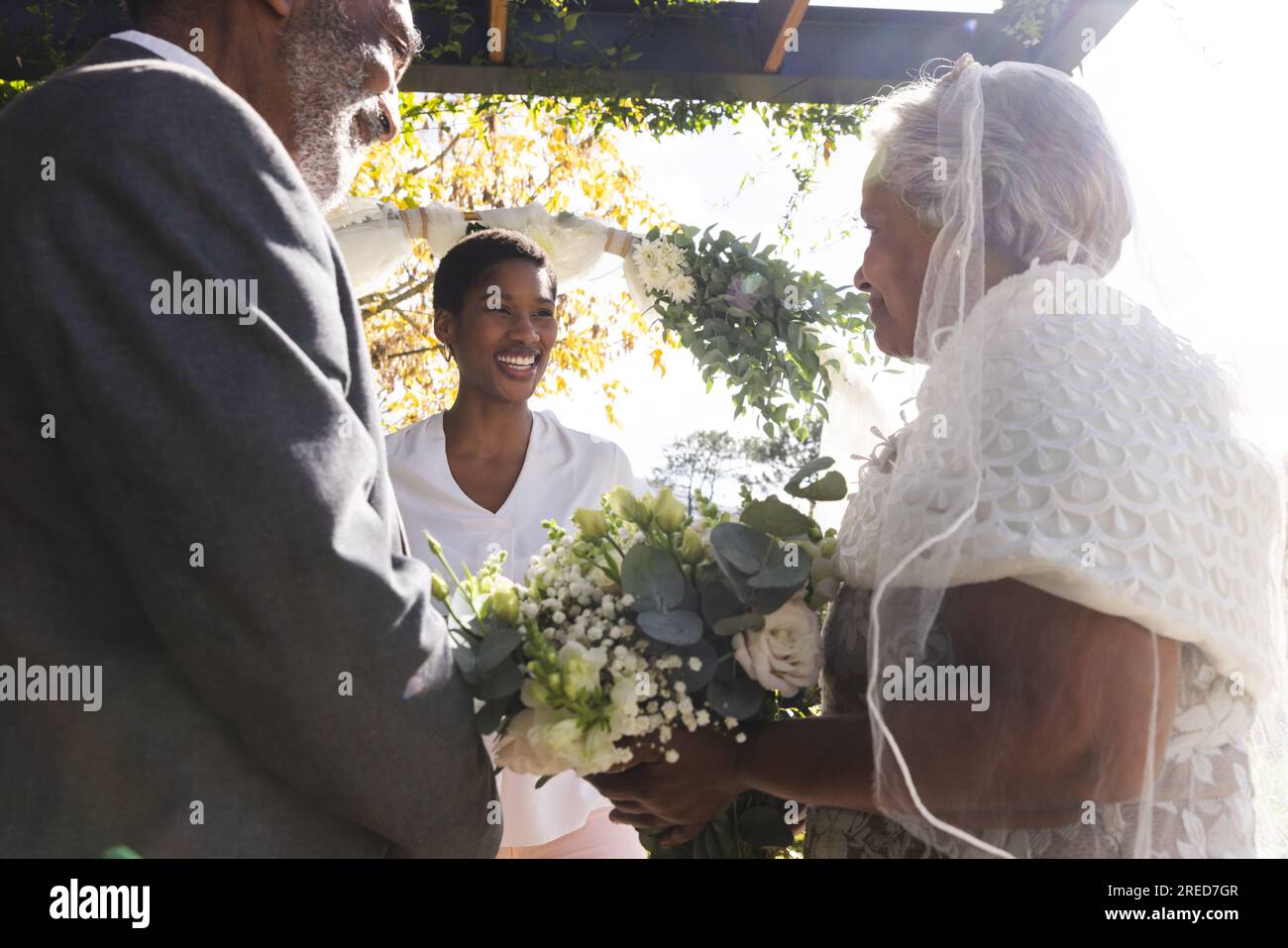 Happy biracial female marriage officiant with senior couple during ...