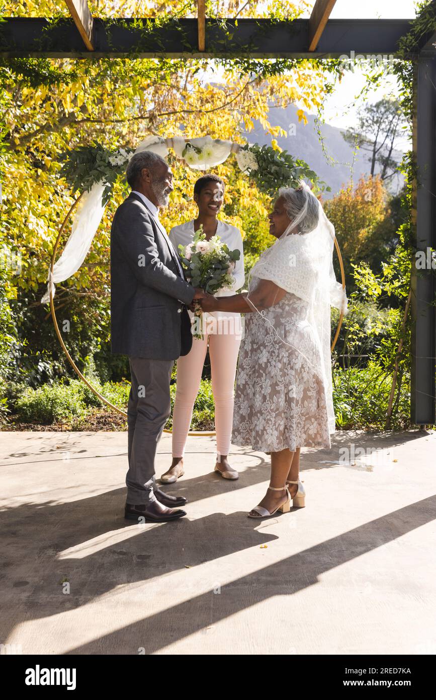 Happy biracial female marriage officiant and senior couple during ...