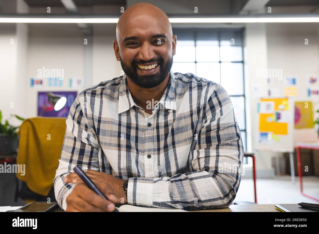 Indian man smiling looking at the camera during a video call at office ...