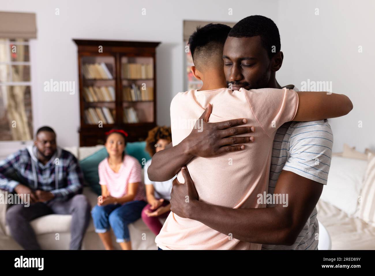 Supportive diverse male friends hugging each other at group therapy ...