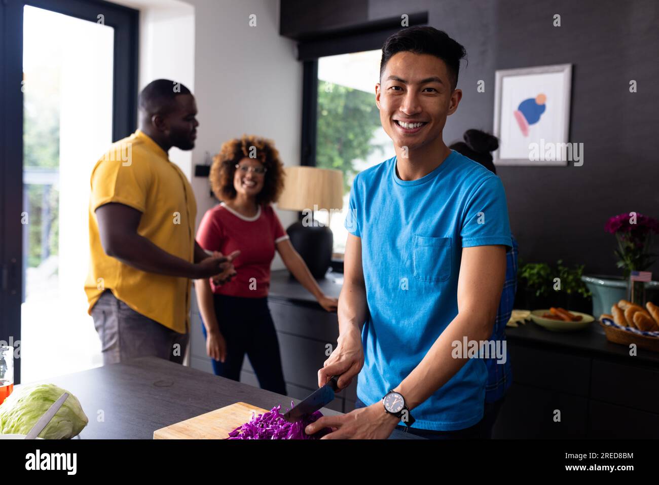 Portrait of happy diverse group of friends cutting vegetables and ...