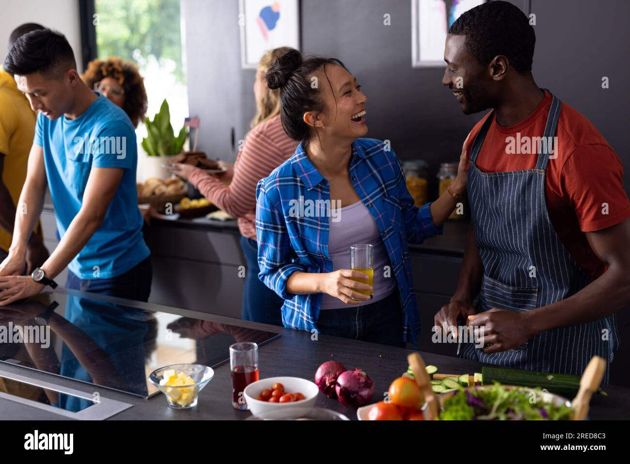 Happy diverse group of friends cooking and talking with drinks in ...