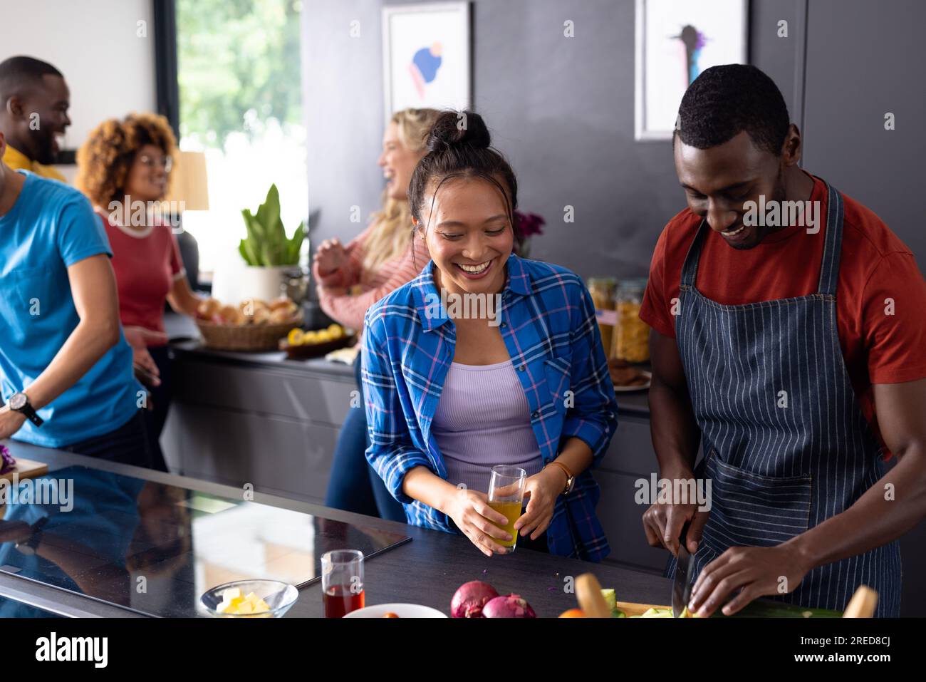 Happy diverse group of friends cooking and talking with drinks in ...