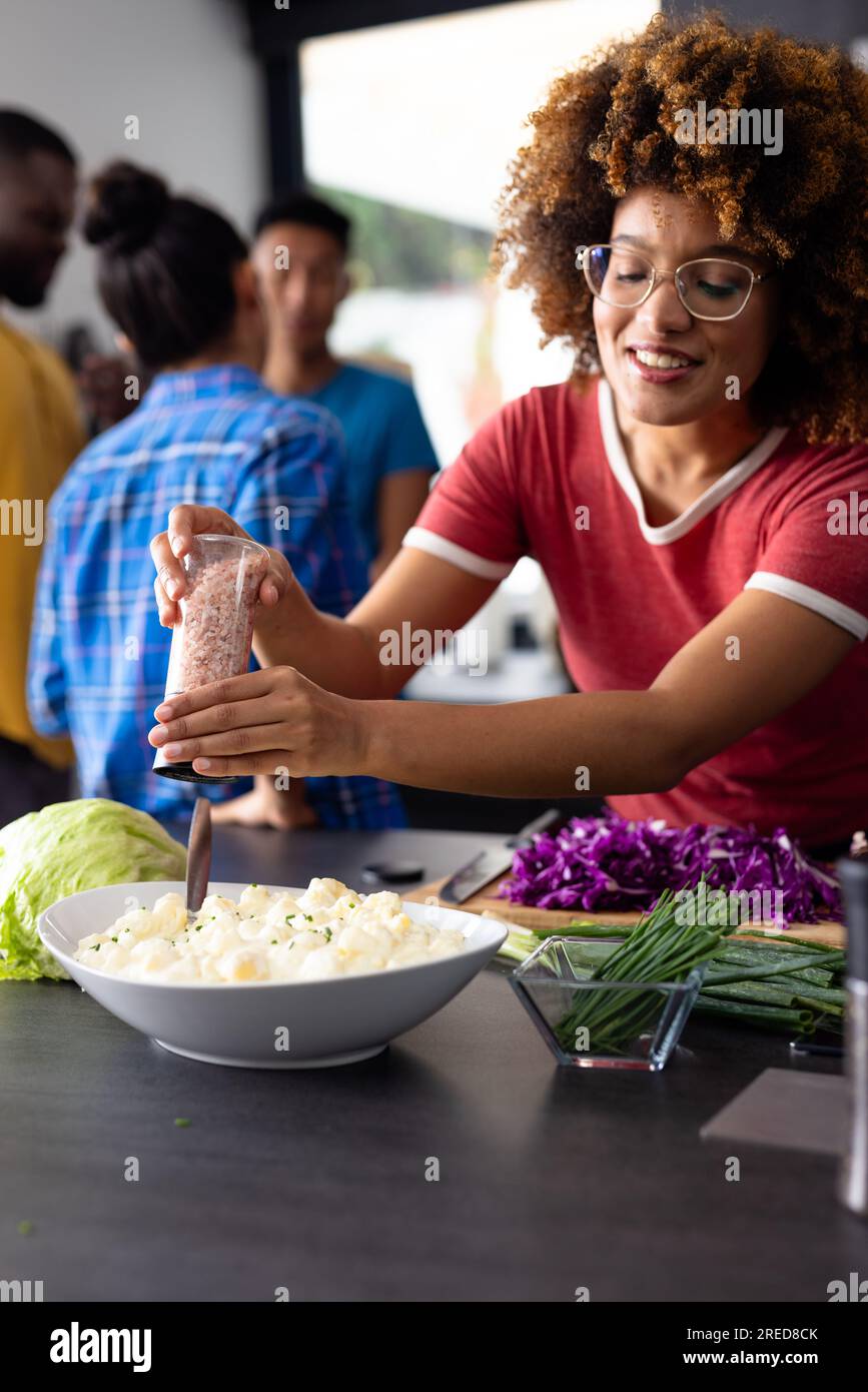 Happy diverse group of friends seasoning and cooking in kitchen Stock ...