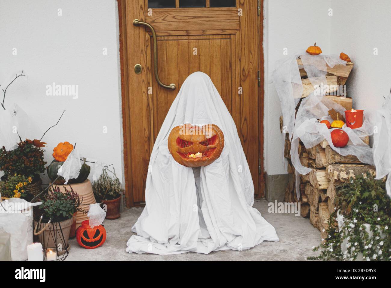 Scary ghost holding Jack o lantern at front of house with spiders web ...
