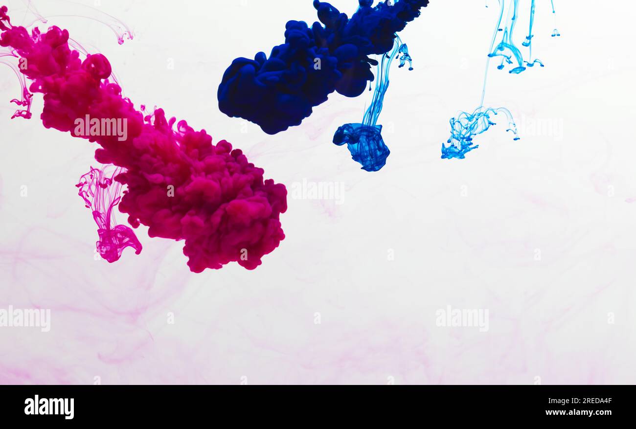 Close up of blue and pink ink in water with copy space on white ...