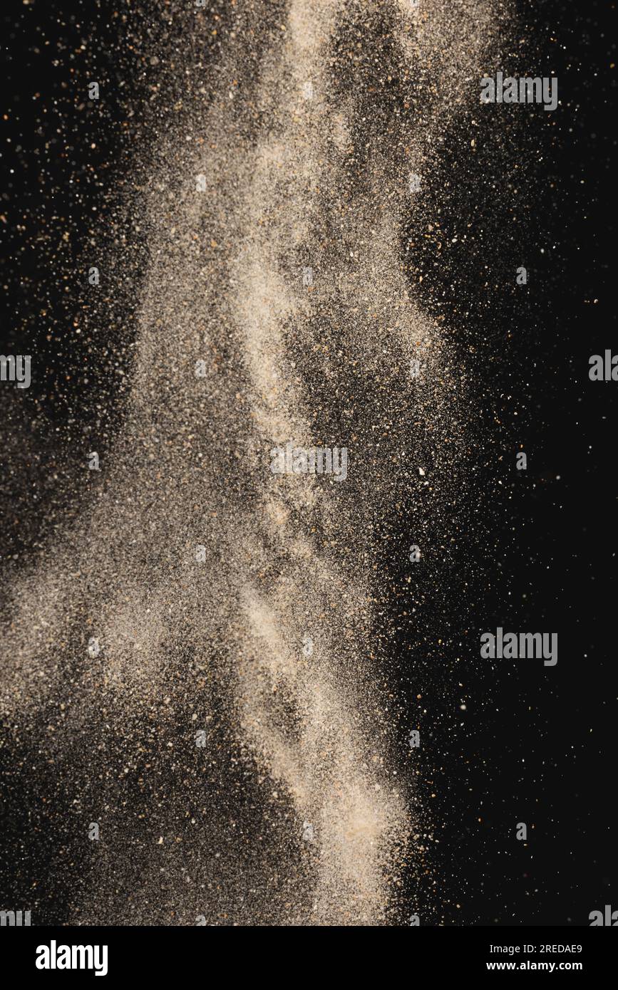 Close up of sand thrown in the air and copy space on black background ...