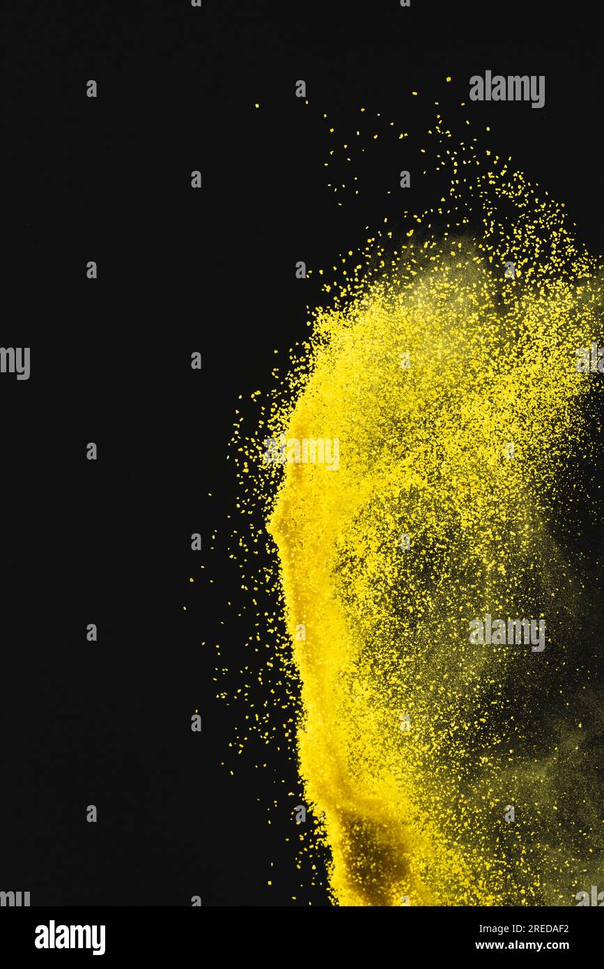Close up of yellow sand thrown in the air and copy space on black ...