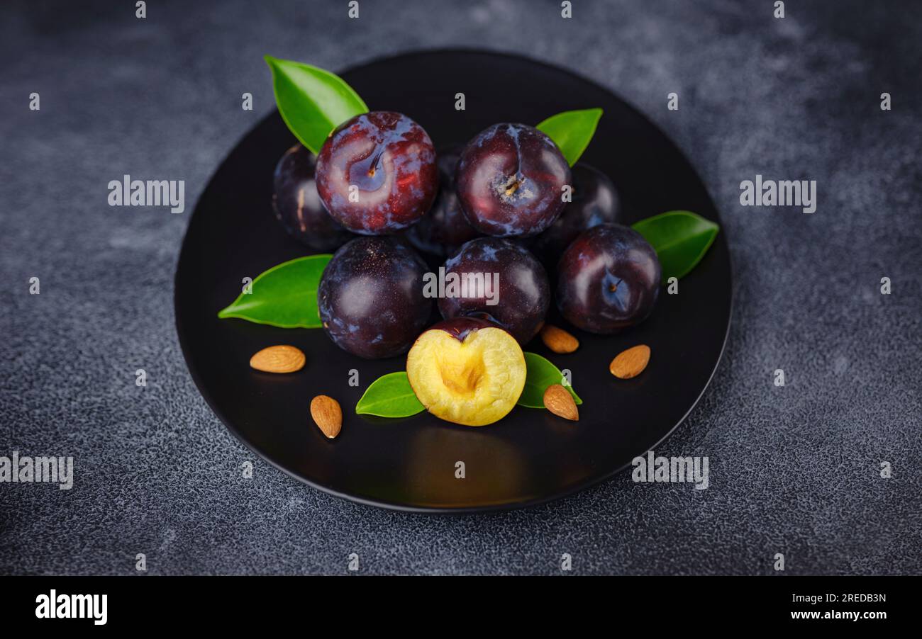 Sweet plums on dark background. Fresh blue plums with leaves. Food ...