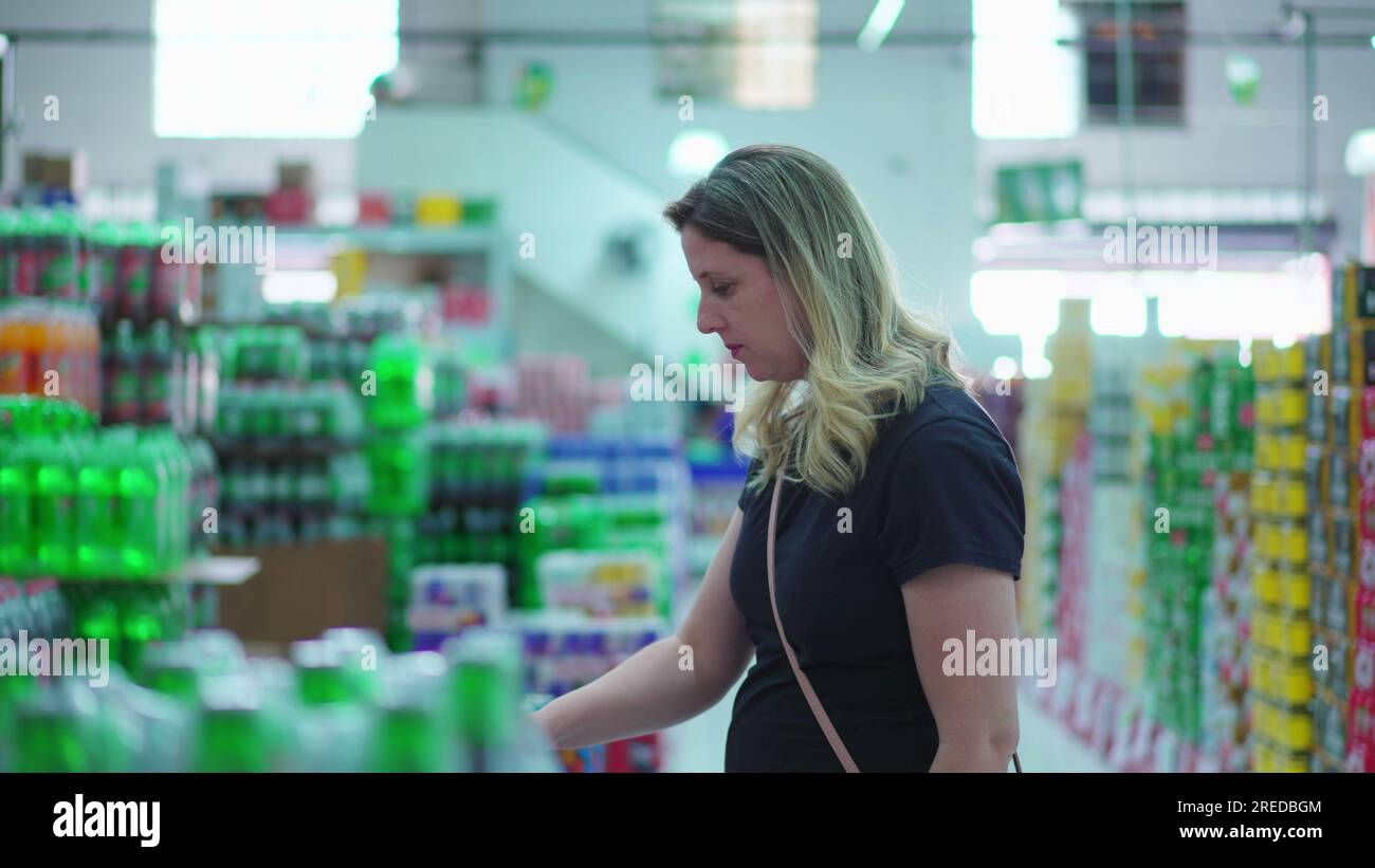 Female consumer browsing products at supermarket. Person pondering ...
