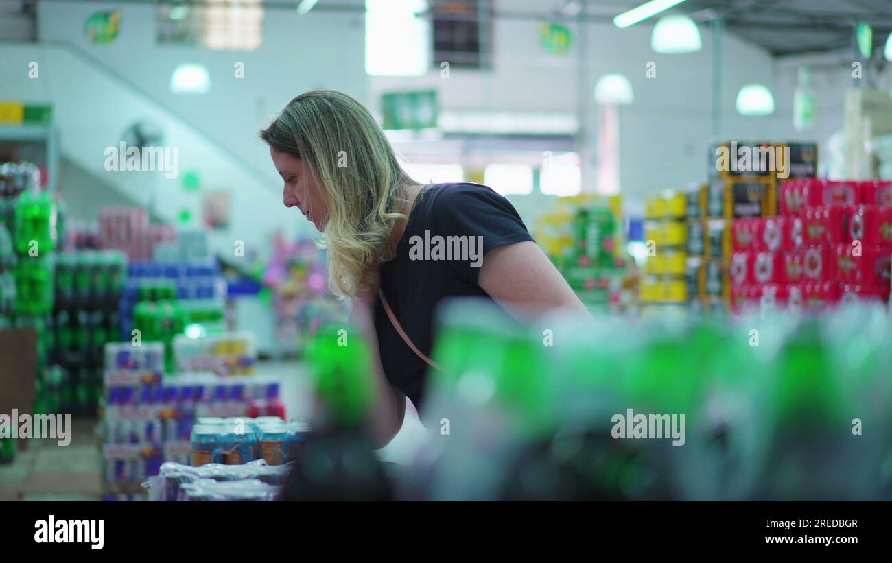 Female consumer browsing products at supermarket. Person pondering ...