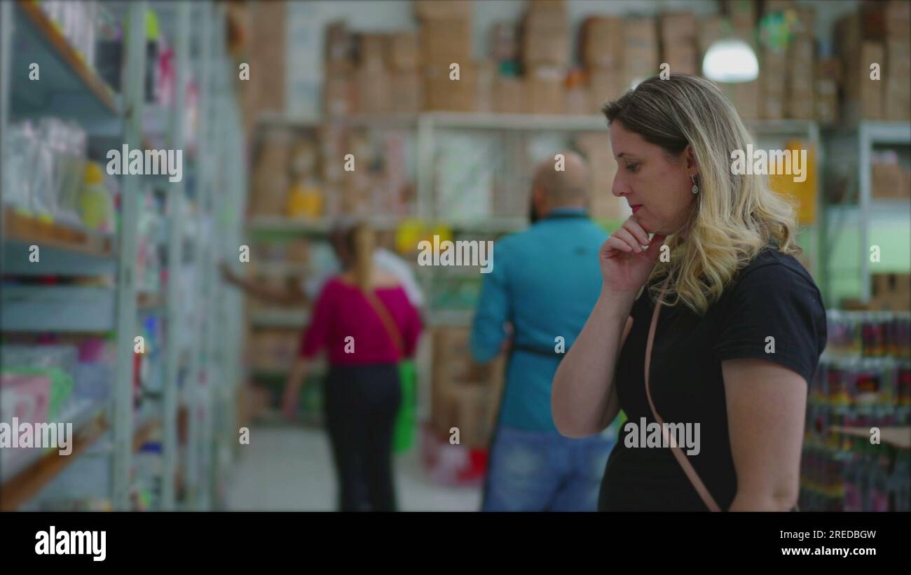 Female consumer looking for products on shelf at grocery store ...