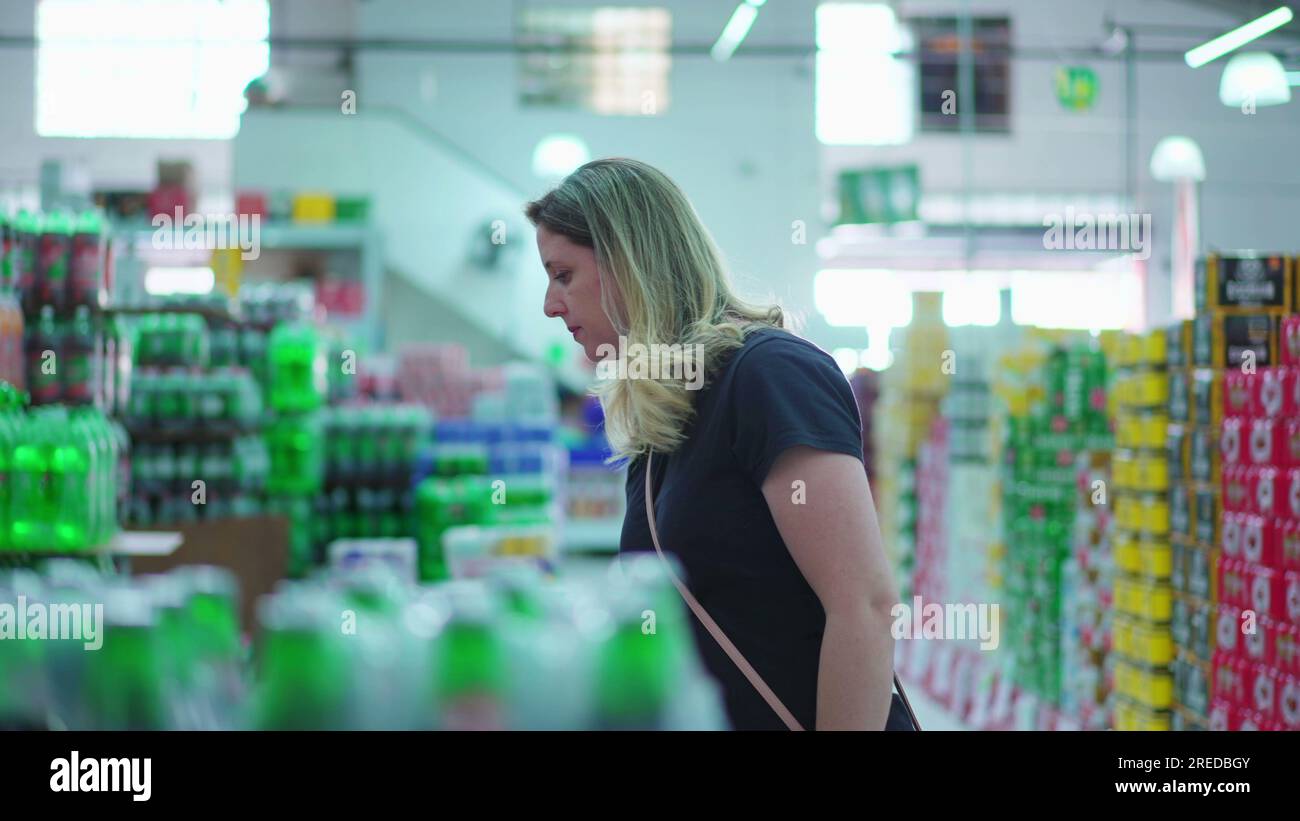 Female consumer browsing products at supermarket. Person pondering ...