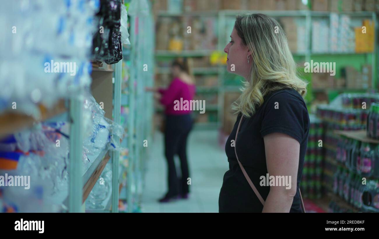 Female shopper browsing products at grocery store shelf. Woman ...