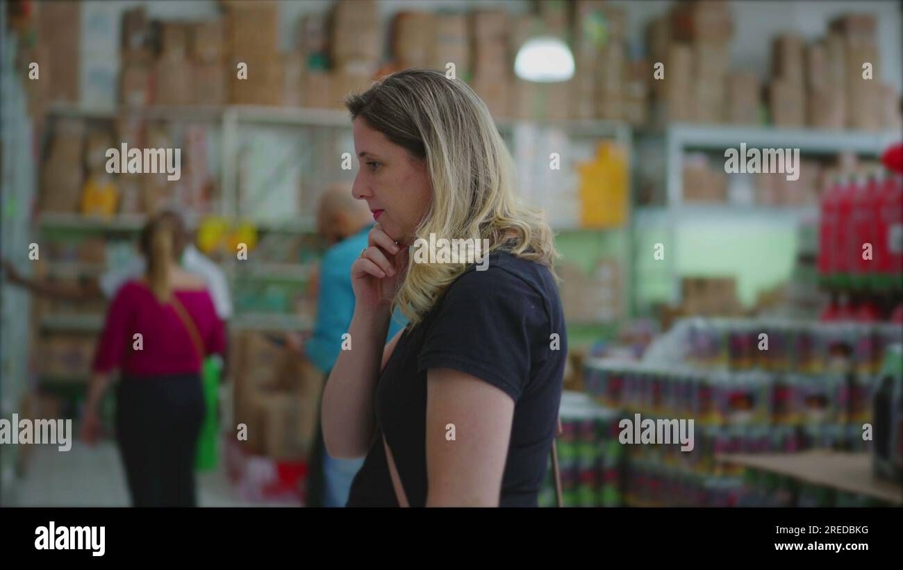 Female consumer looking for products on shelf at grocery store ...