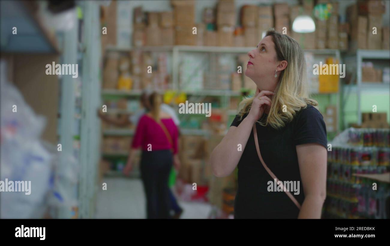 Female consumer looking for products on shelf at grocery store ...