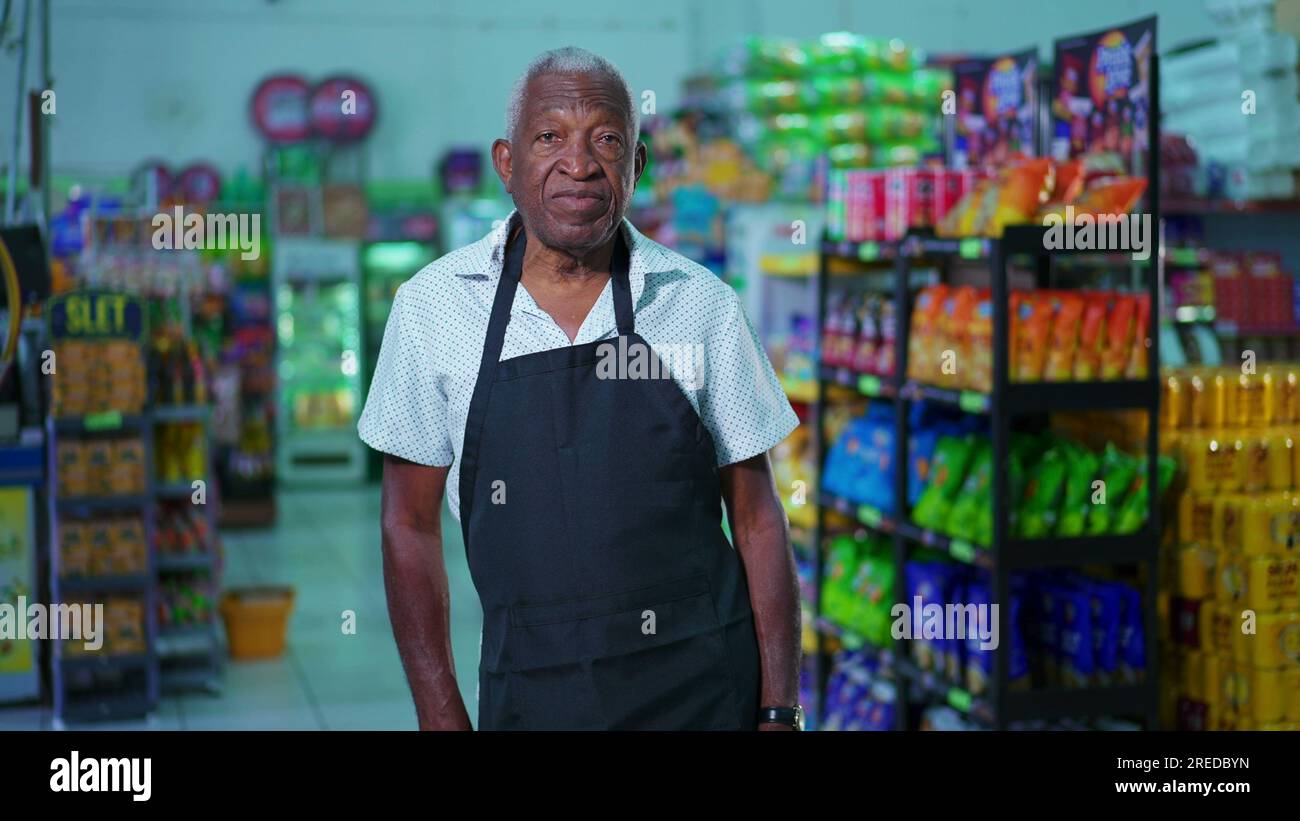 One senior black male employee of supermarket standing inside ...