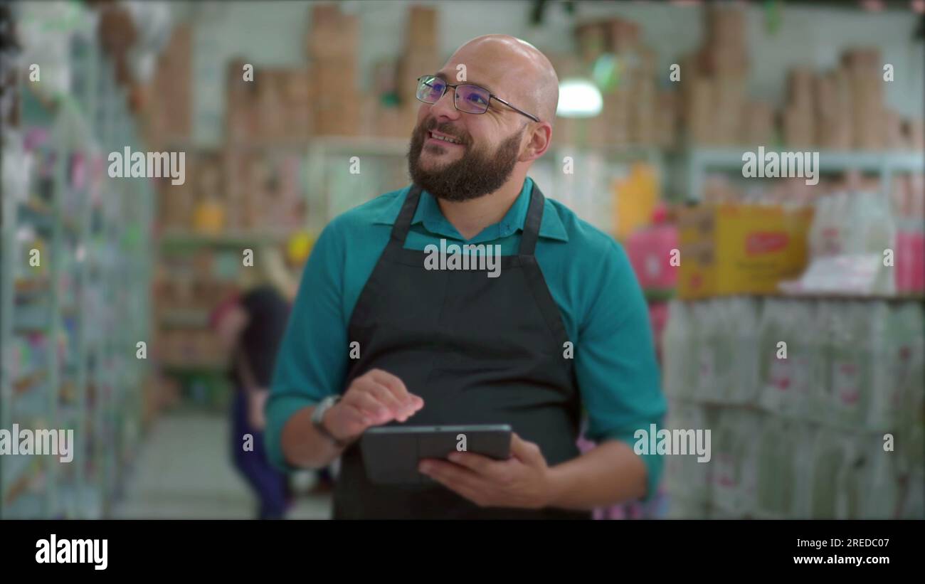 Happy employee walking in Grocery Store aisle with tablet device ...