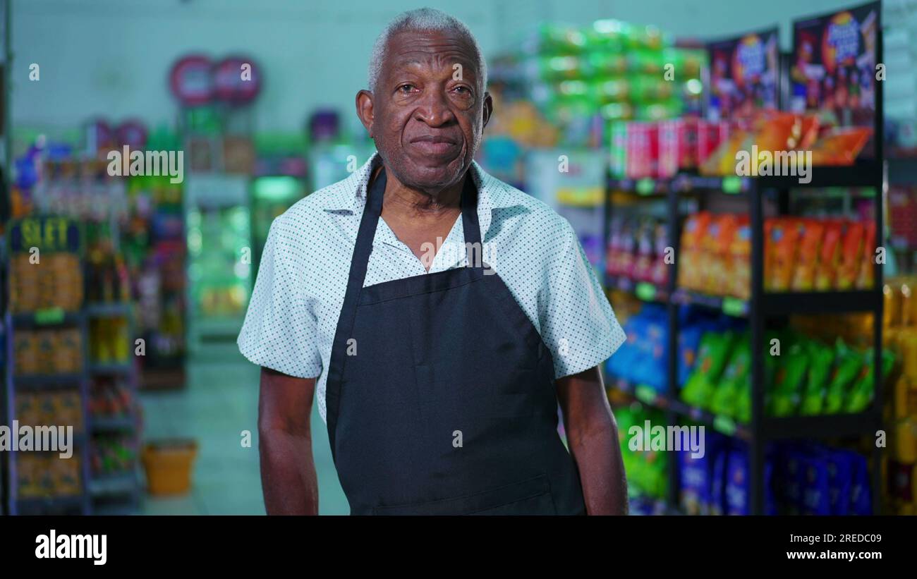 One senior black male employee of supermarket standing inside ...