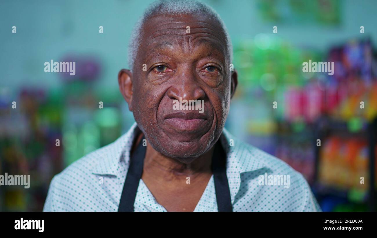 One senior black male employee of supermarket standing inside ...