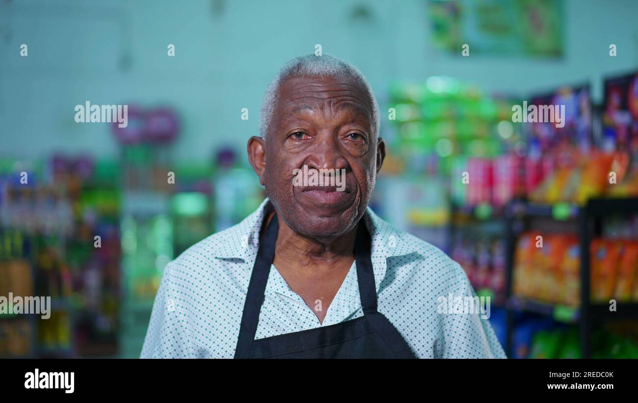 One senior black male employee of supermarket standing inside ...