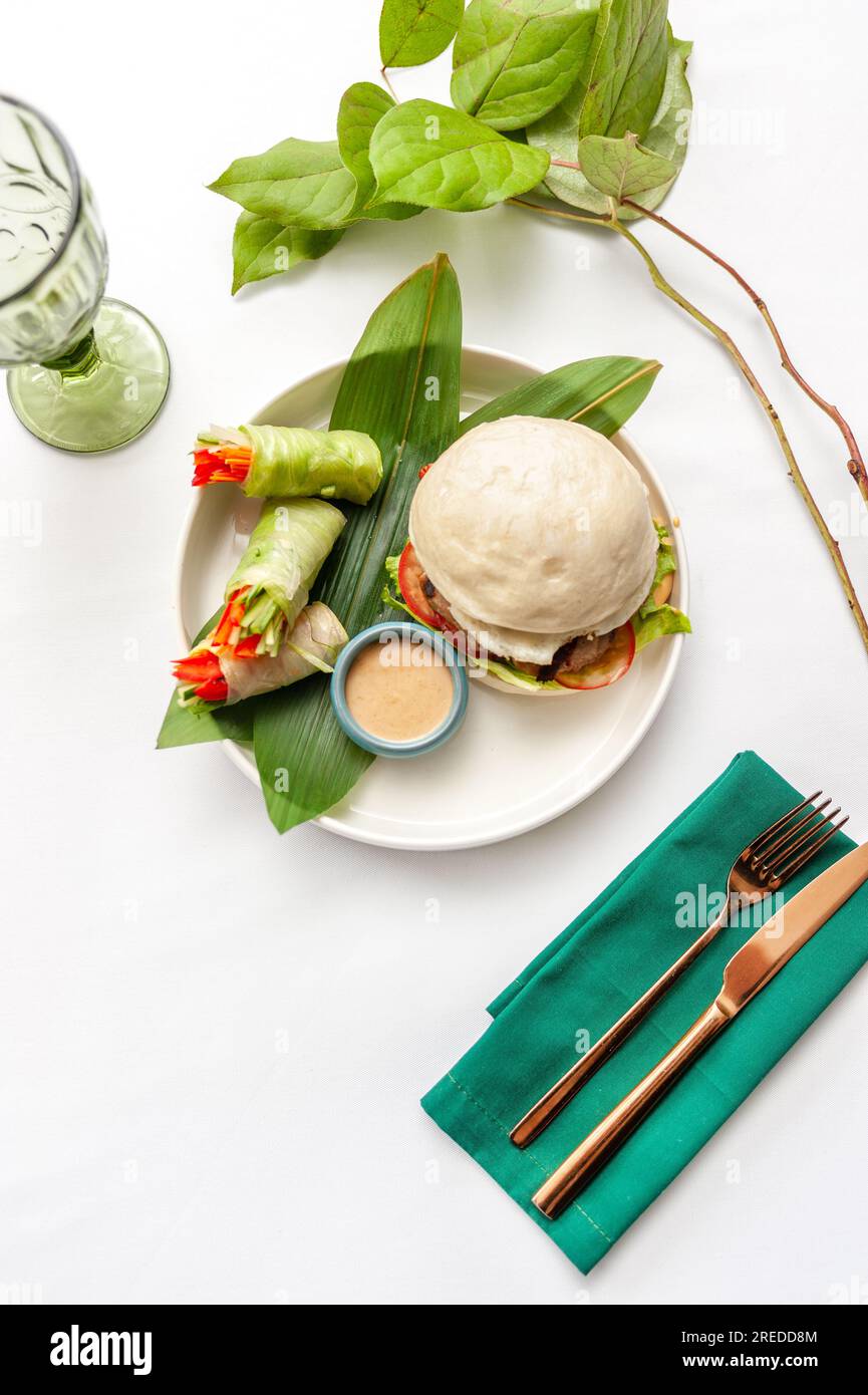 Burger with Bao steamed buns, spring rolls and sesame sauce Stock Photo ...