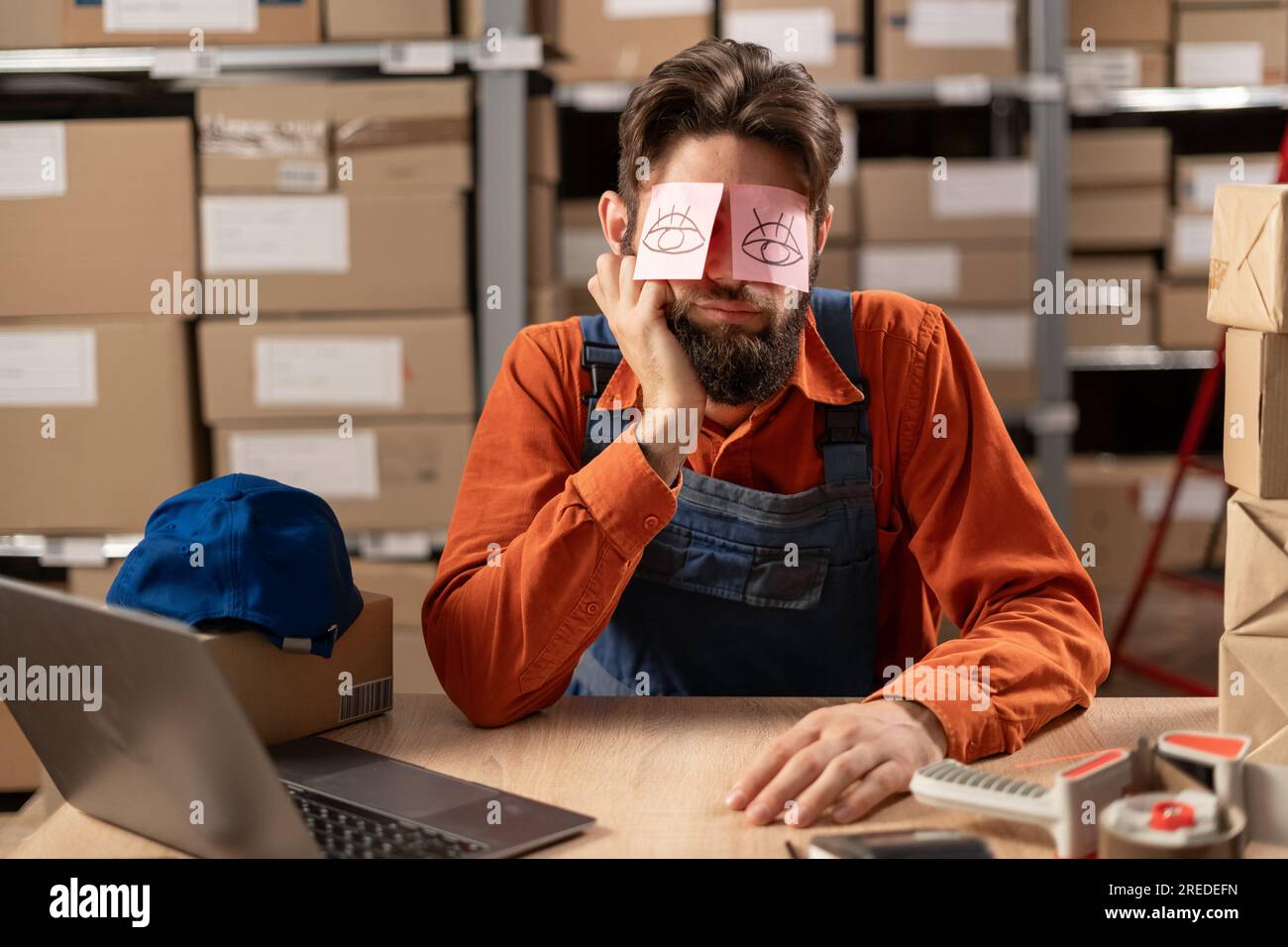 Exhausted tired warehouse worker with painted eyes on stickers ...