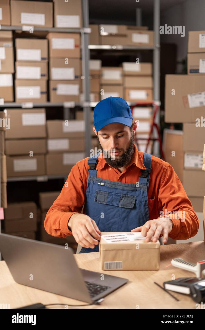 Warehouse worker applying shipping label on parcel boxes. Copy space ...