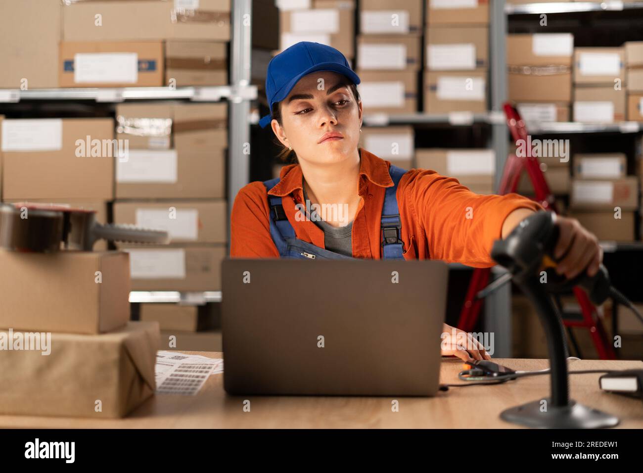 Young female worker working with laptop computer and using barcode ...