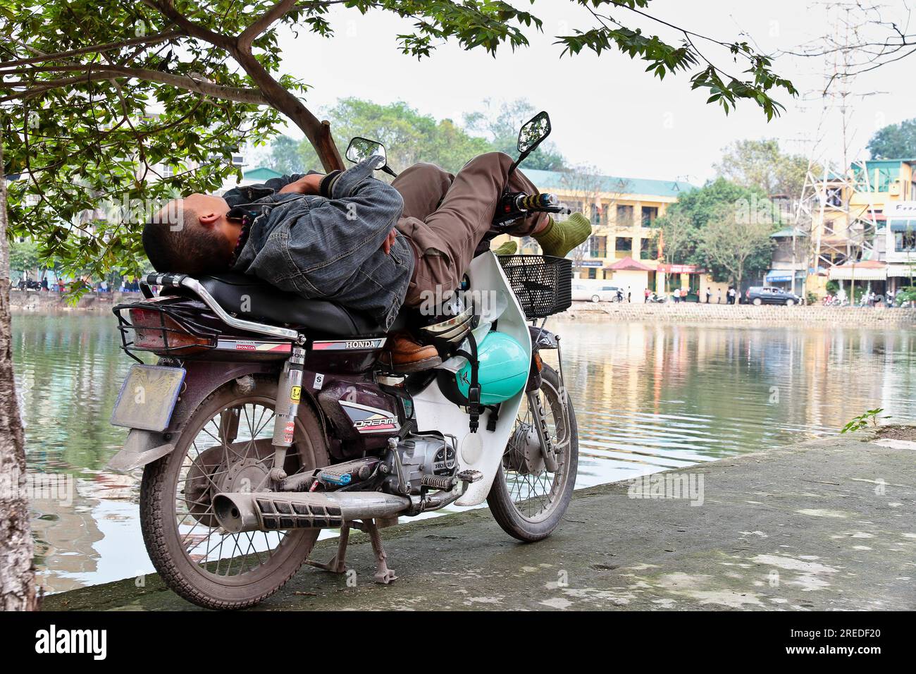 Driver sleeping on his motorcycle at the West Lake in Hanoi in Vietnam ...